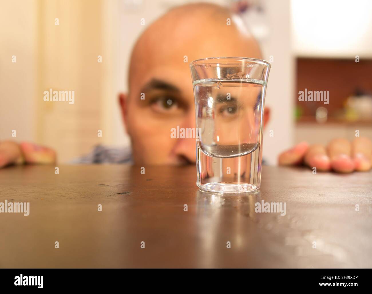 Addicted man looking at a glass filled with alcohol Stock Photo - Alamy