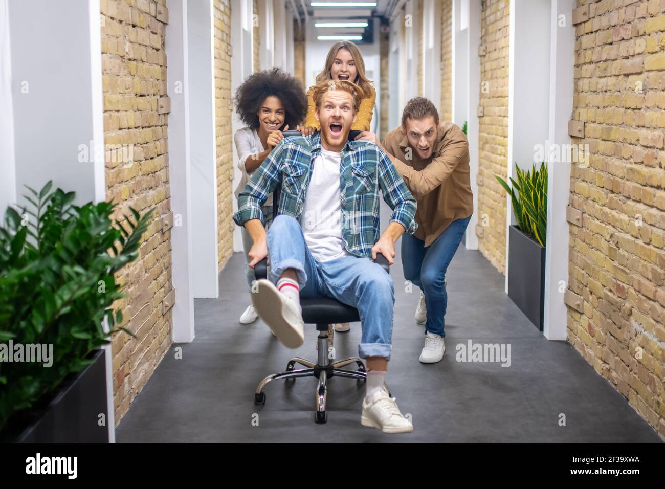 Having fun. Group of friends having fun in the office corridor after a ...