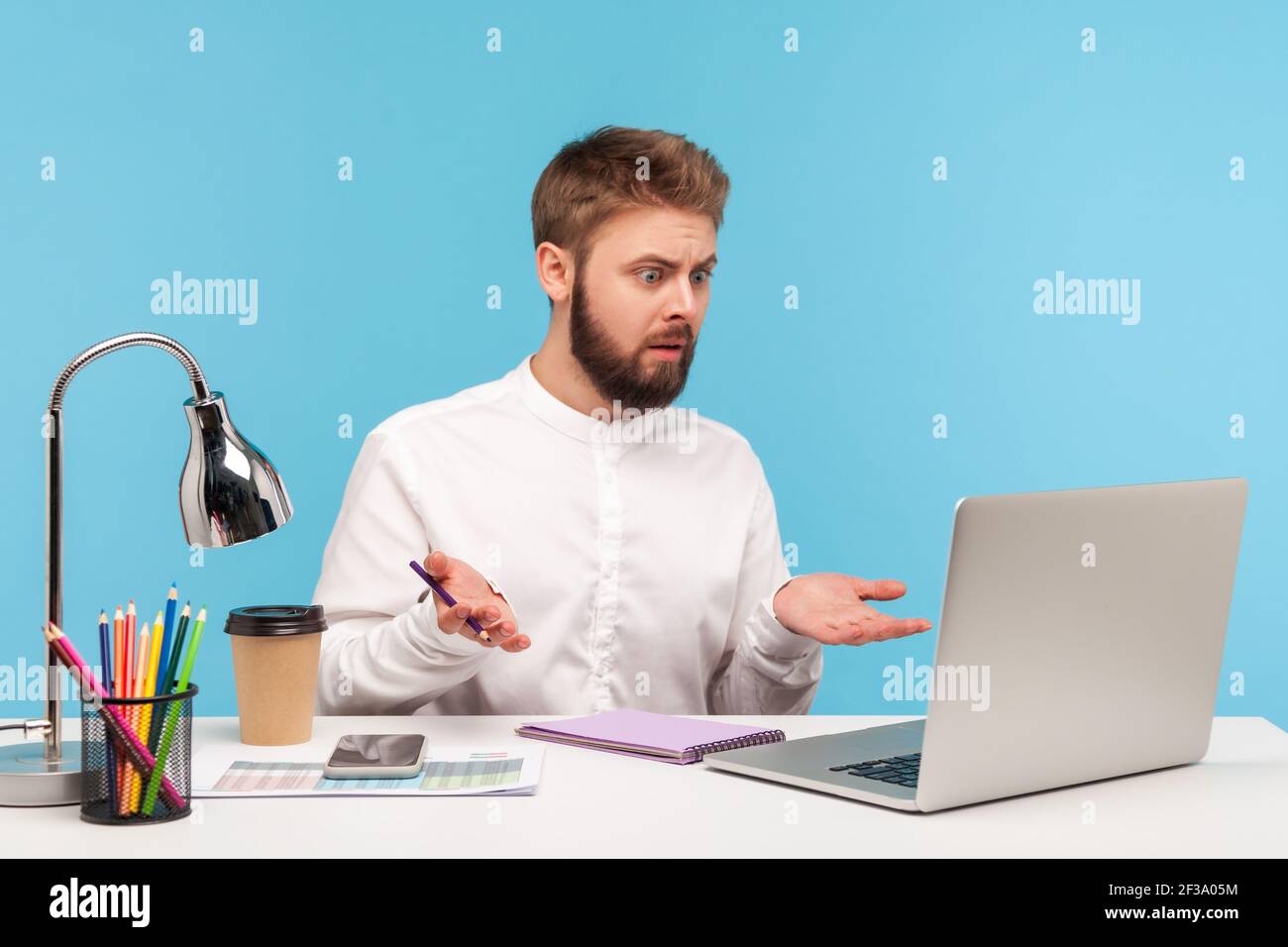 Unhappy confused man office worker spreading hands looking at laptop ...