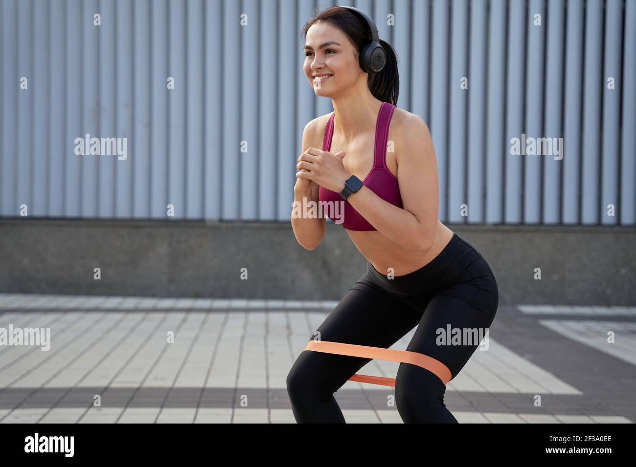 Pretty woman with wireless headphones doing squats Stock Photo - Alamy