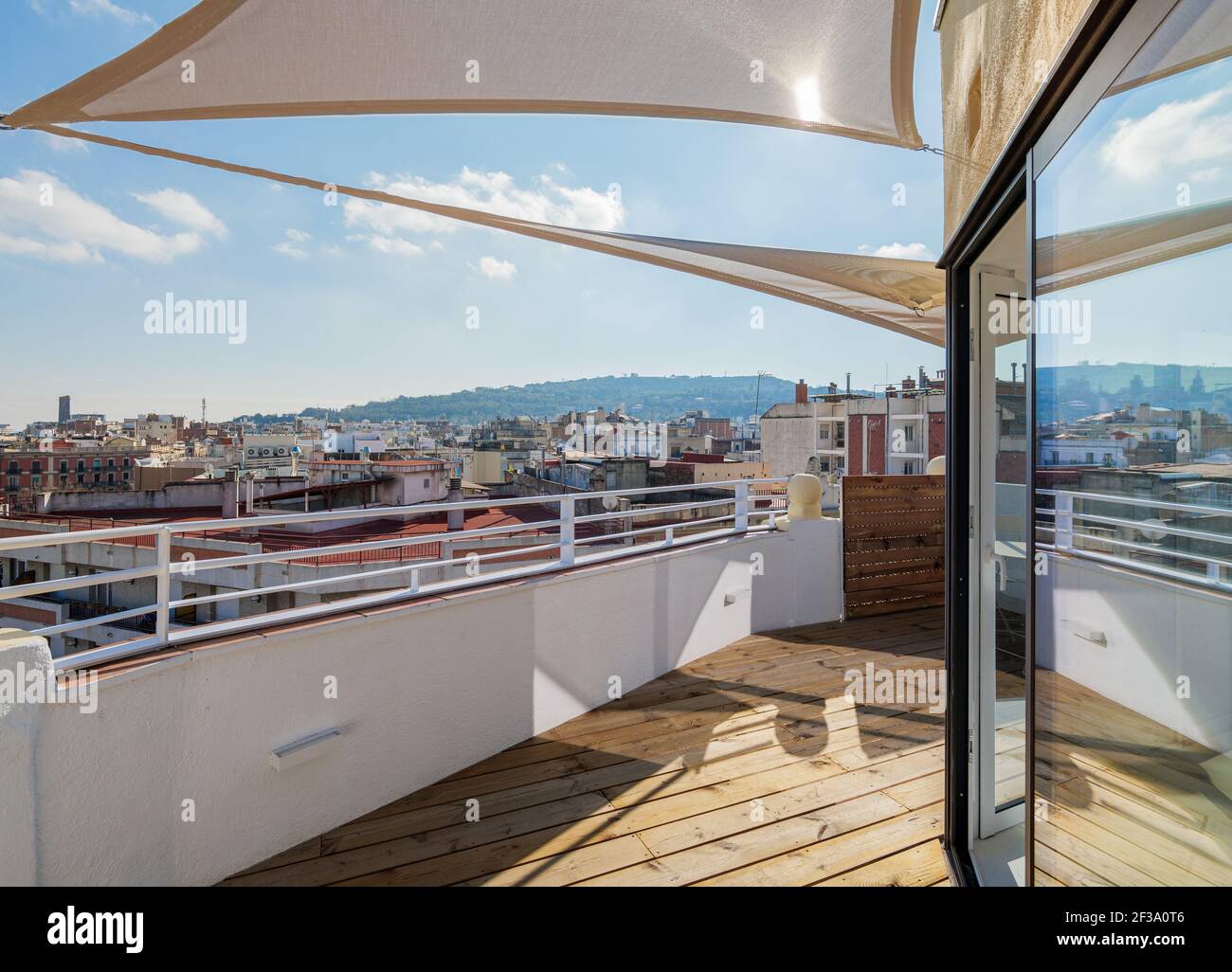 Sunny empty terrace with a sunshade. View to the hill and the city ...