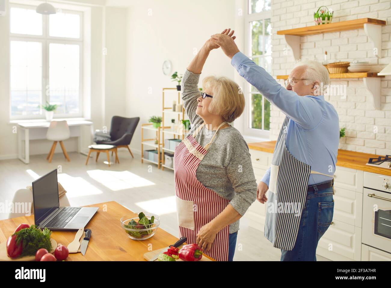Positive senior couple having fun while cooking a healthy meal at home ...