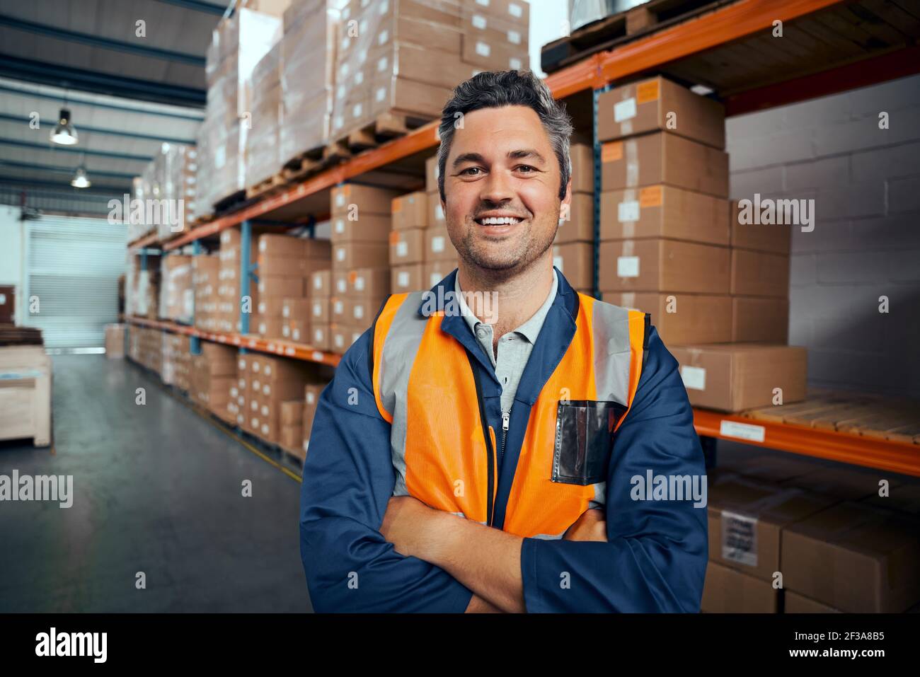 Smiling portrait of a male supervisor standing in warehouse with his ...