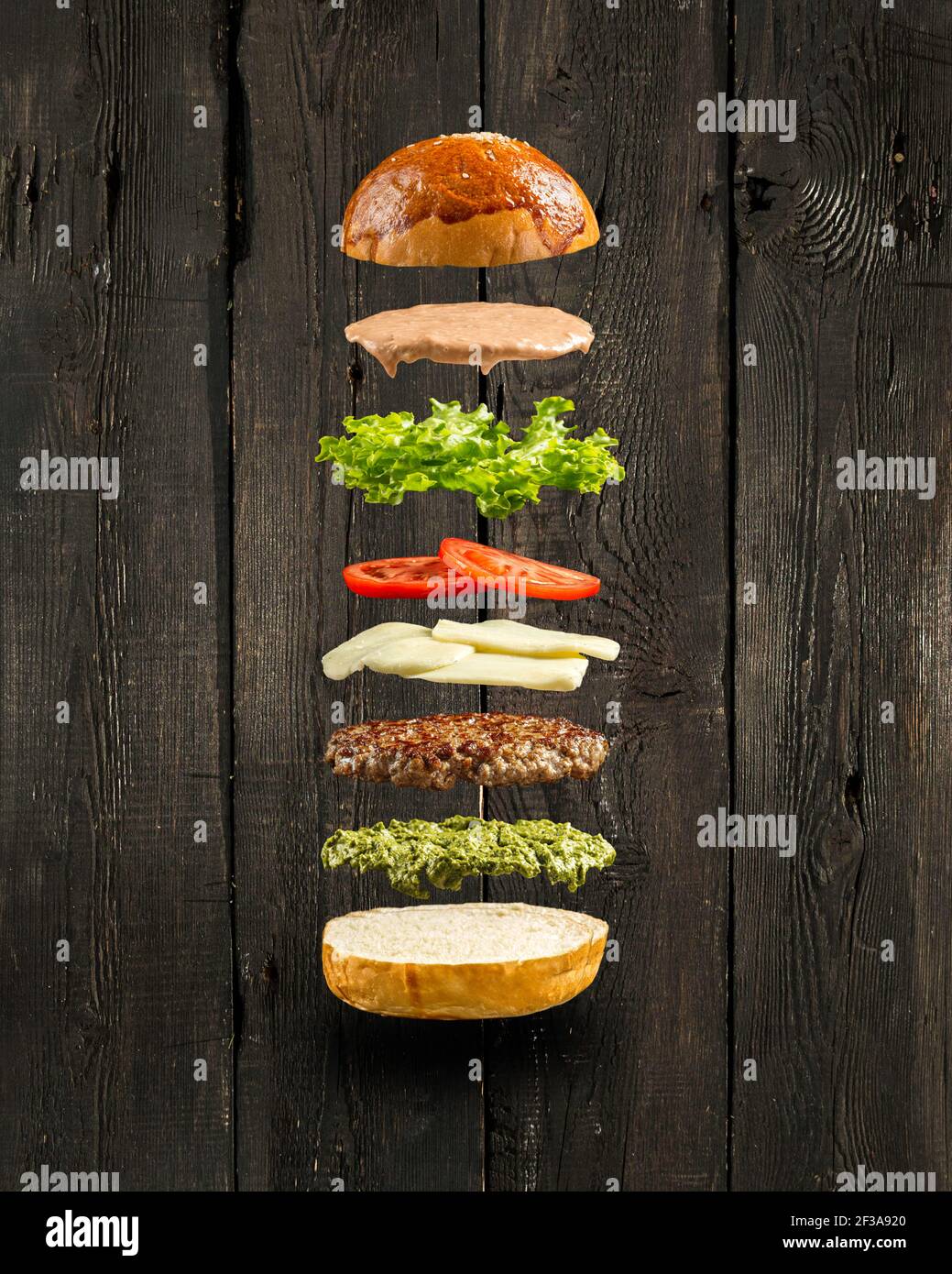 Floating burger ingredients on the wooden background Stock Photo - Alamy