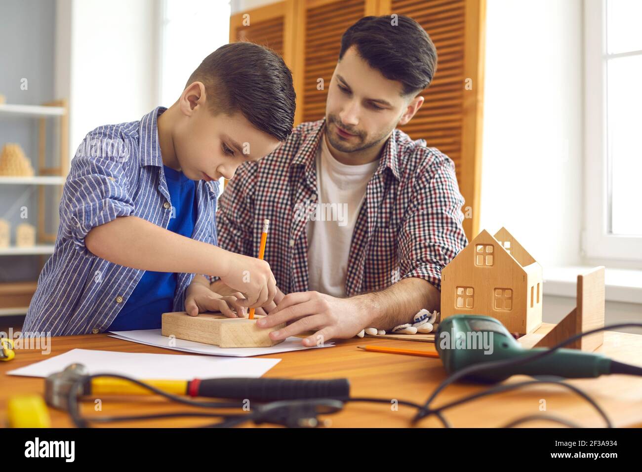 Caring father carpenter in the workshop teaches his little interested ...