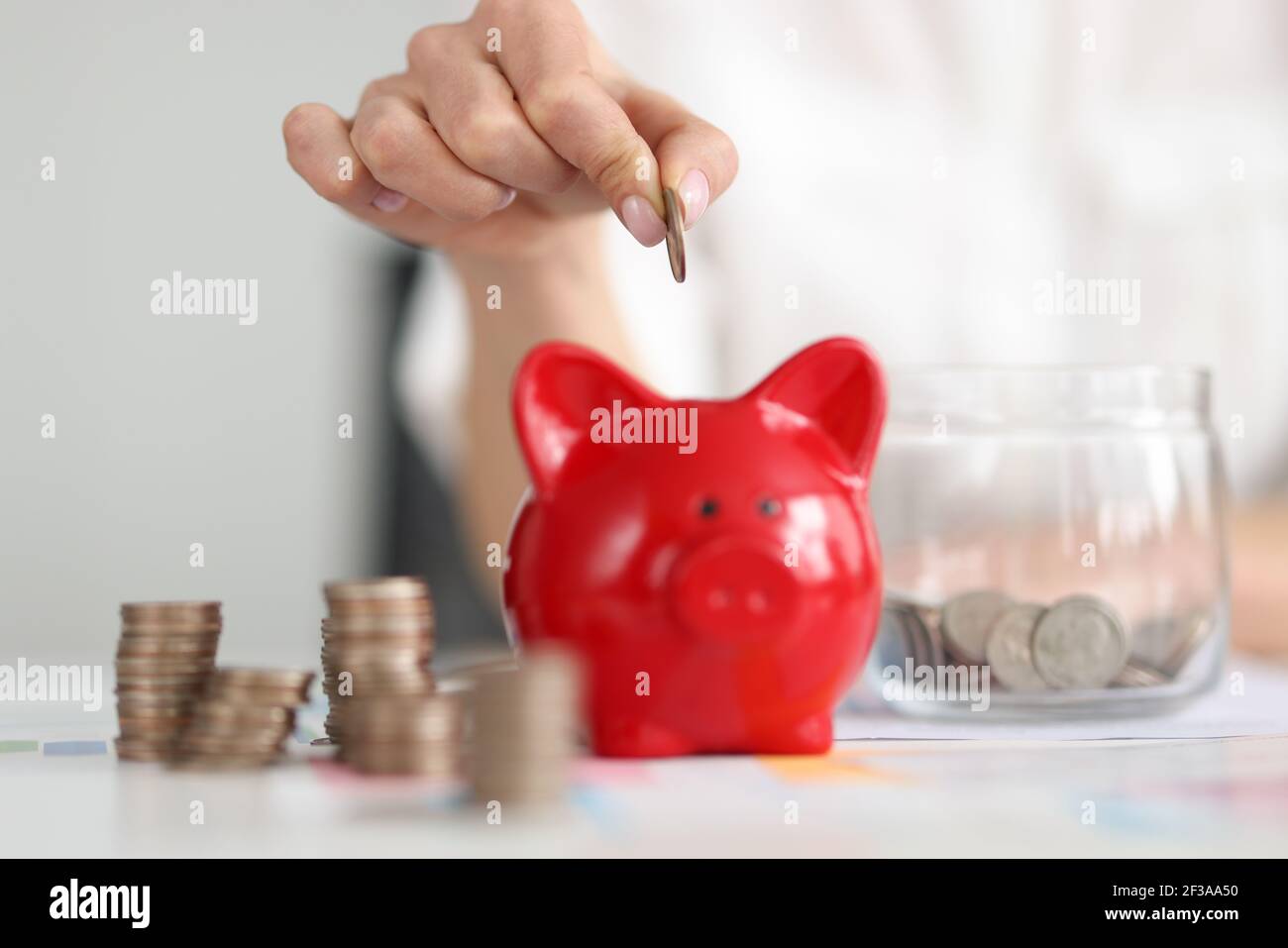 Womans hand putting coin in piggy bank closeup Stock Photo - Alamy
