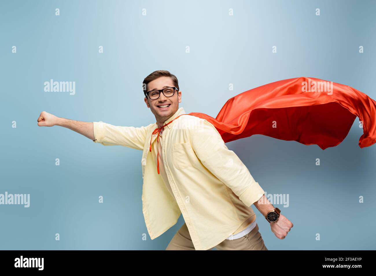 happy superhero in glasses and red cape standing with outstretched hand ...