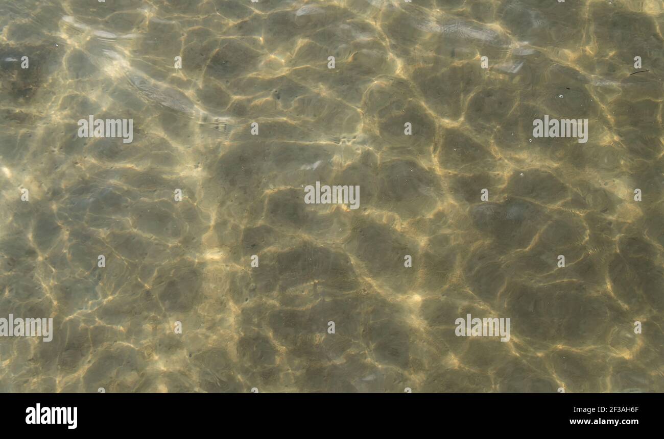 Sunshine on gentle ripples in shallow warm sea-water. Background, copy ...
