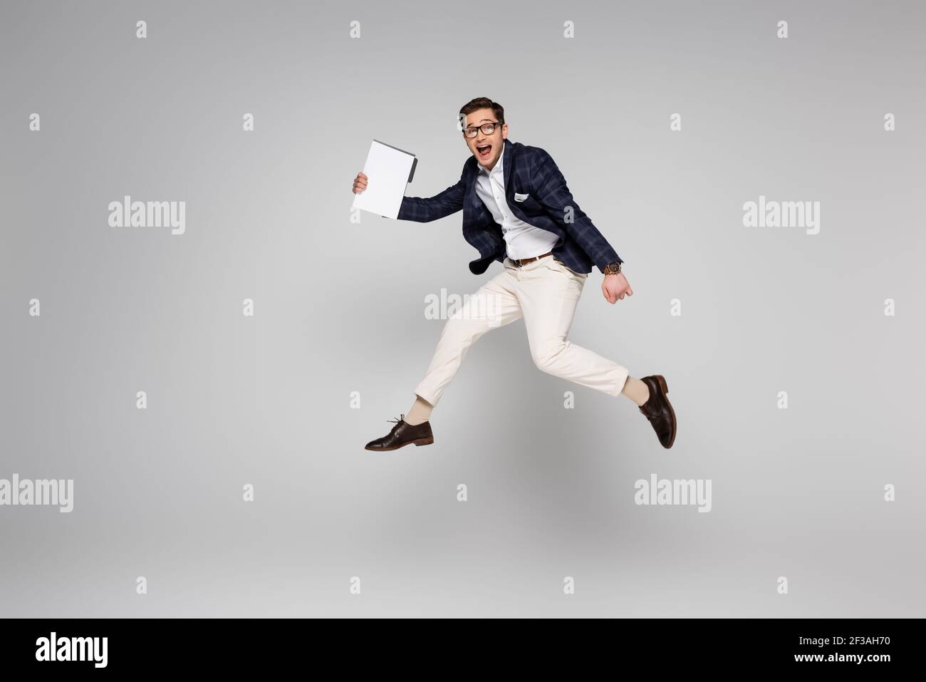 full length of young businessman holding paper folder while flying on ...