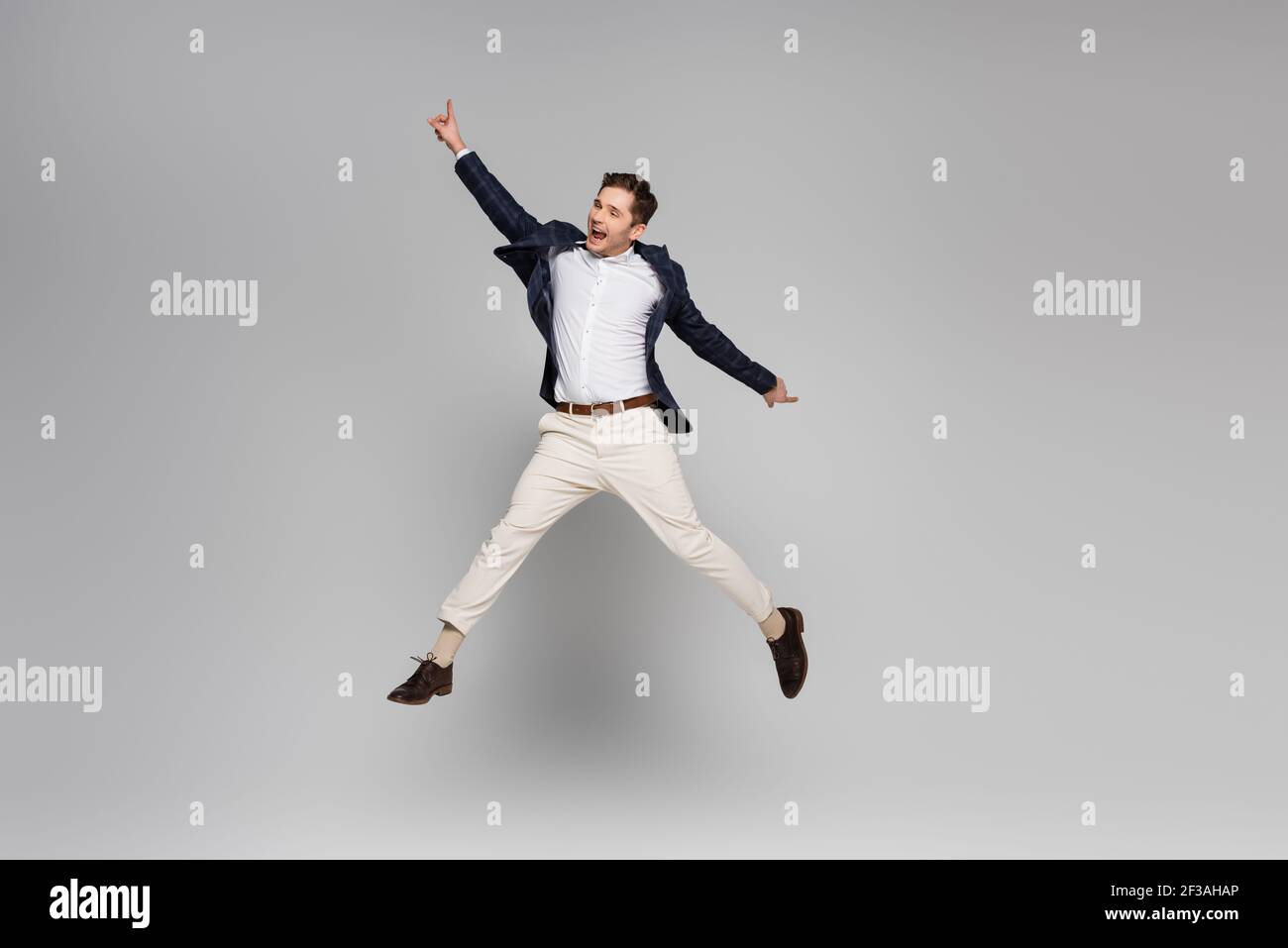 full length of excited young man with outstretched hands levitating on ...