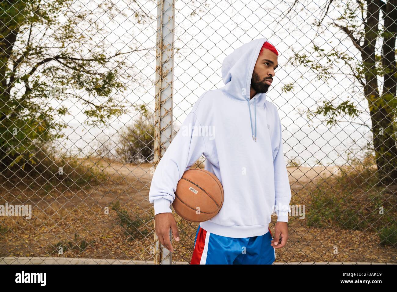 Bearded african american guy standing with basketball at playground ...