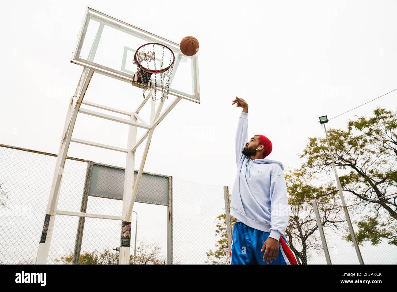 Bearded african american guy in earphones playing basketball at ...
