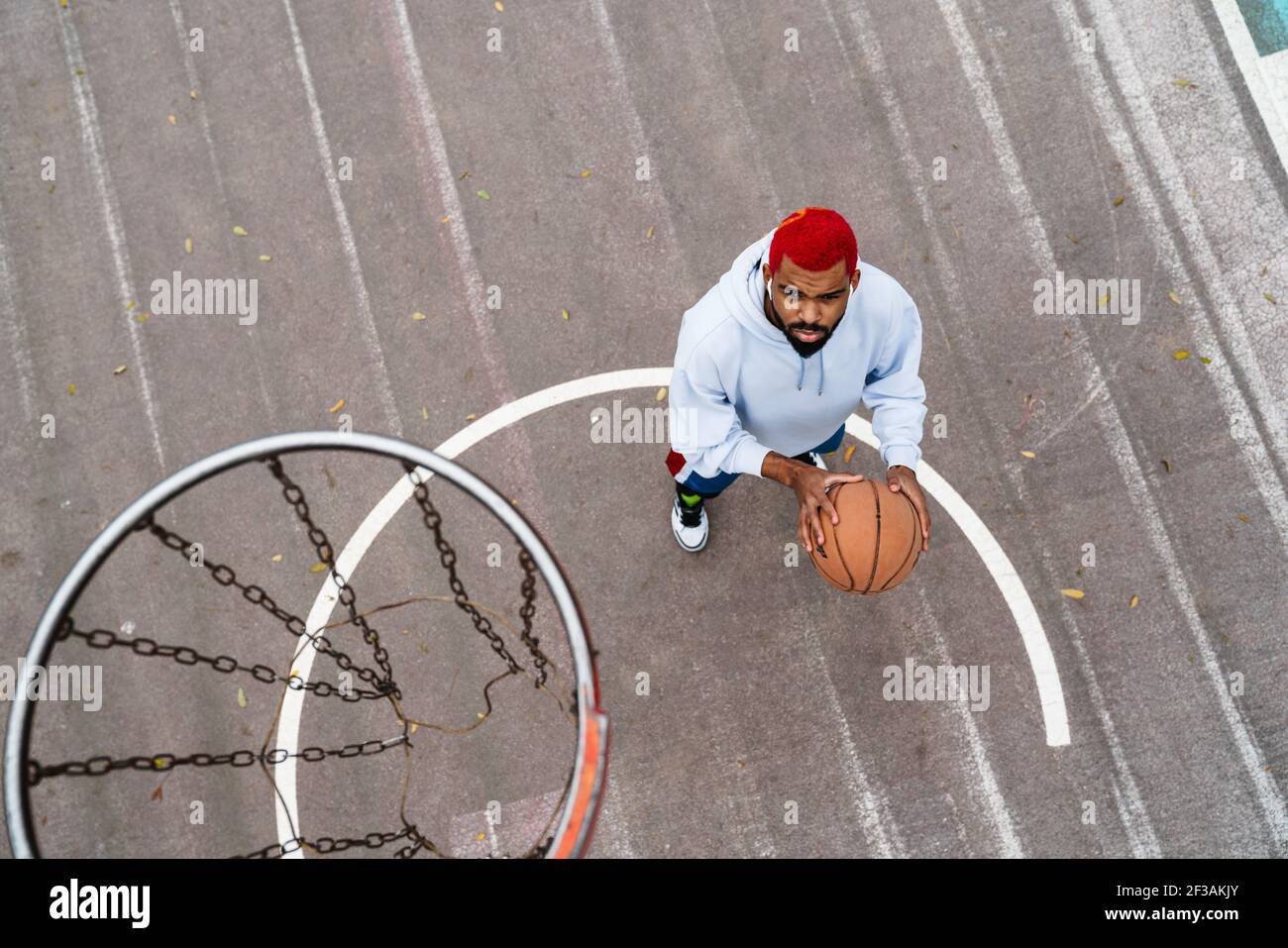 Bearded african american guy in earphones playing basketball at ...