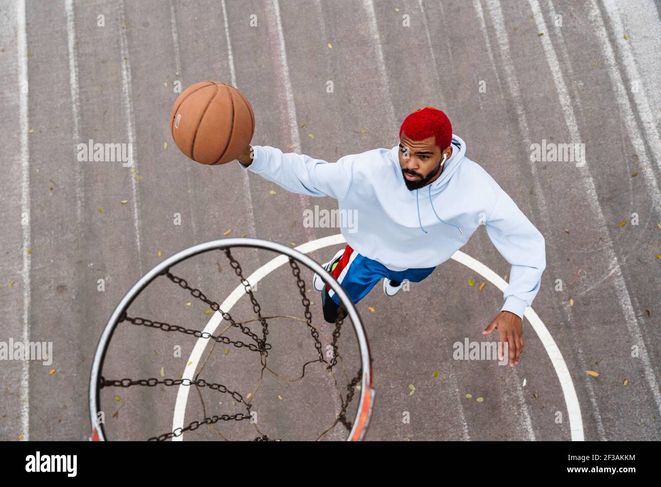 Bearded african american guy in earphones playing basketball at ...