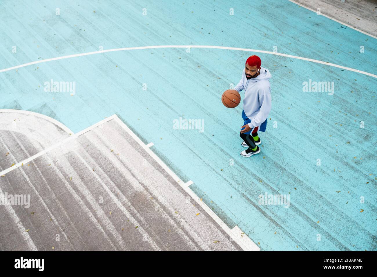 Bearded african american guy in earphones playing basketball at ...