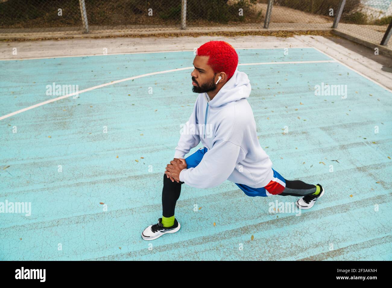 Bearded african american guy in earphones doing exercise on playground ...