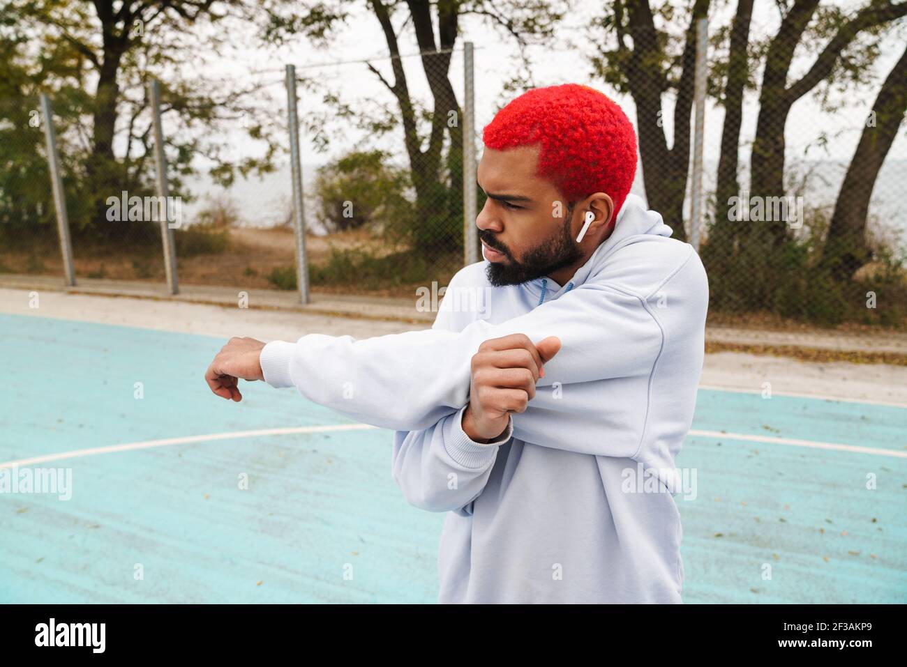 Bearded african american guy in earphones doing exercise on playground ...