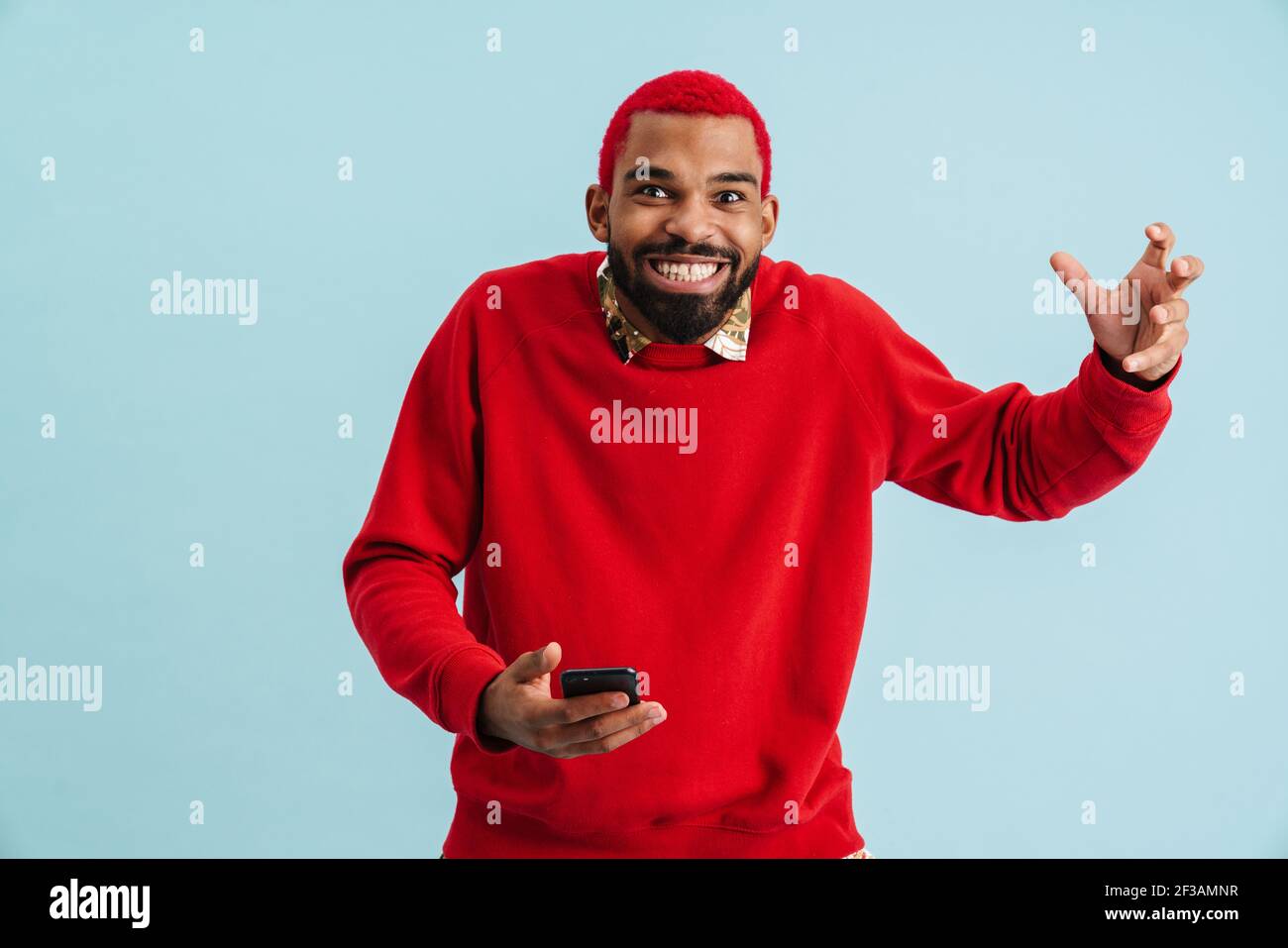 Happy african american guy making fun while using mobile phone isolated ...
