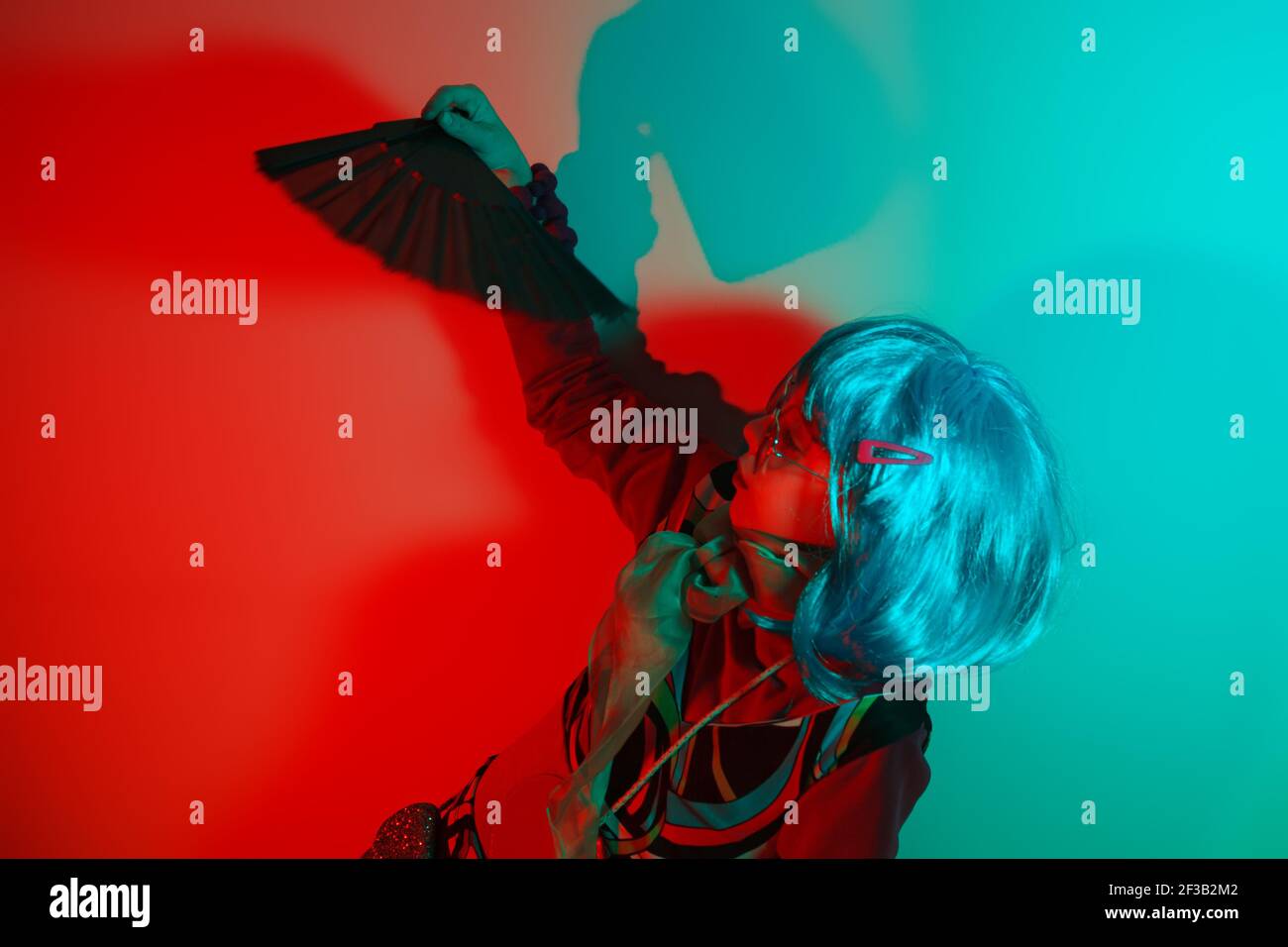 Little girl posing with a fan for a photo shoot on a red and cyan ...