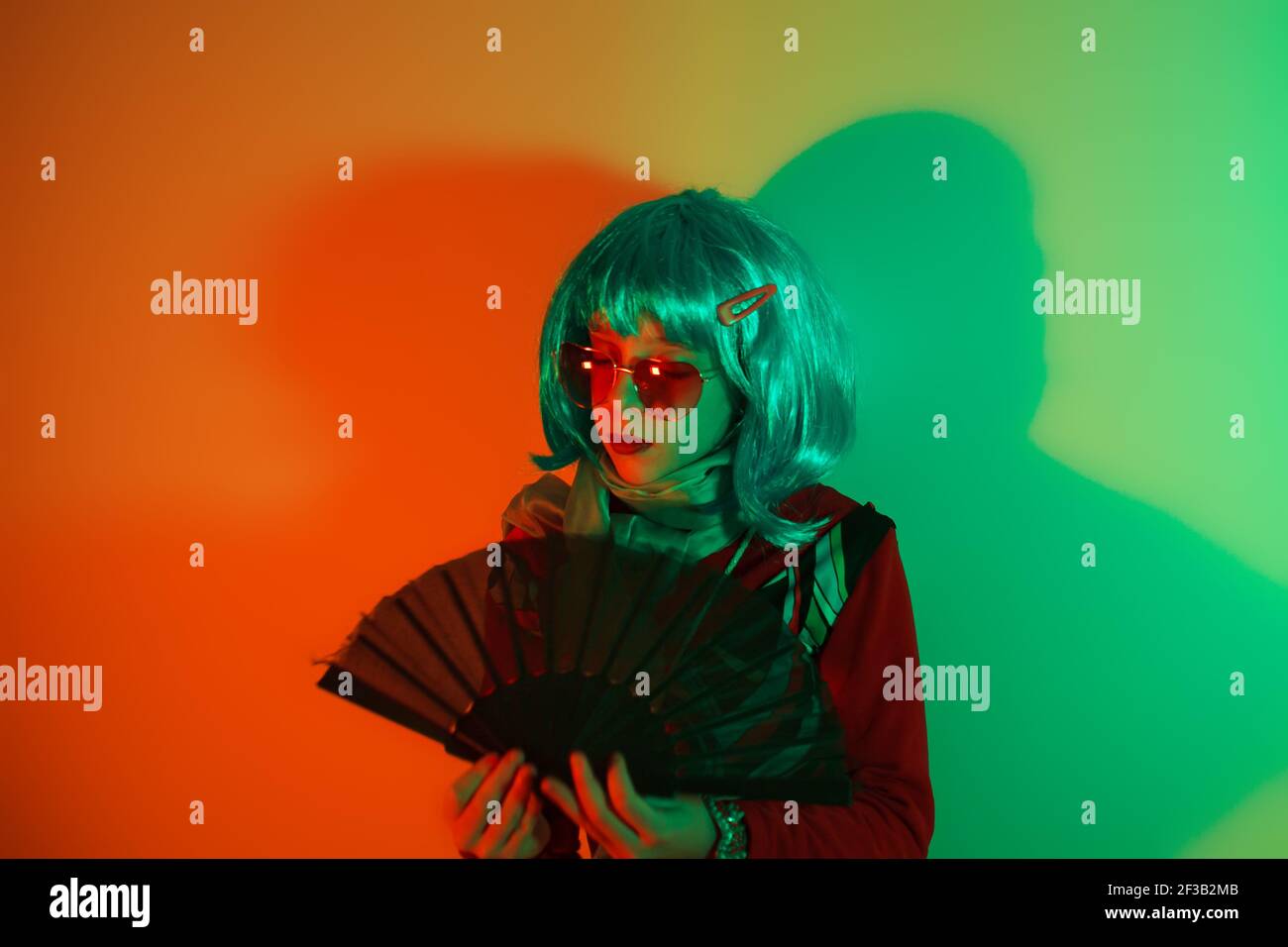 Little girl posing with a fan for a photo shoot on a orange and green ...