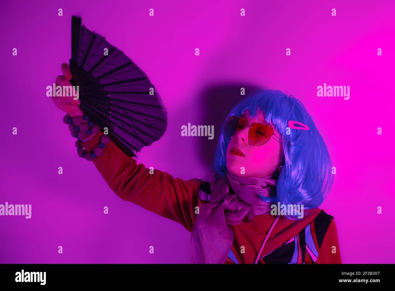 Little girl posing with a fan for a photo shoot on a fuchsia background ...