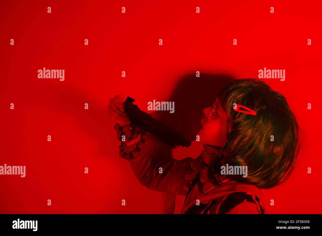 Little girl posing with a fan for a photo shoot on a red background ...