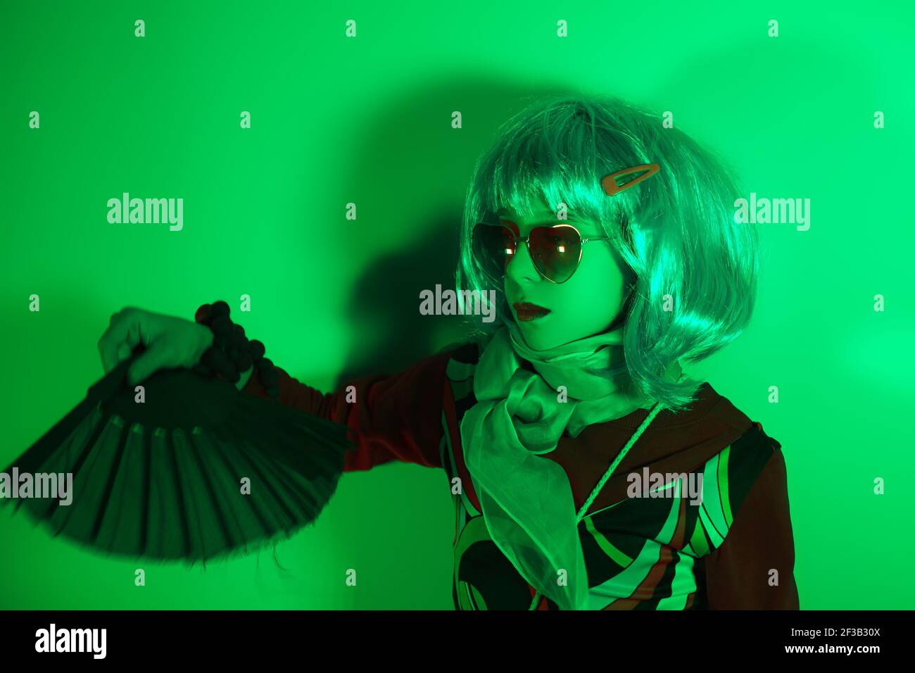 Little girl posing with a fan for a photo shoot on a fuchsia background ...