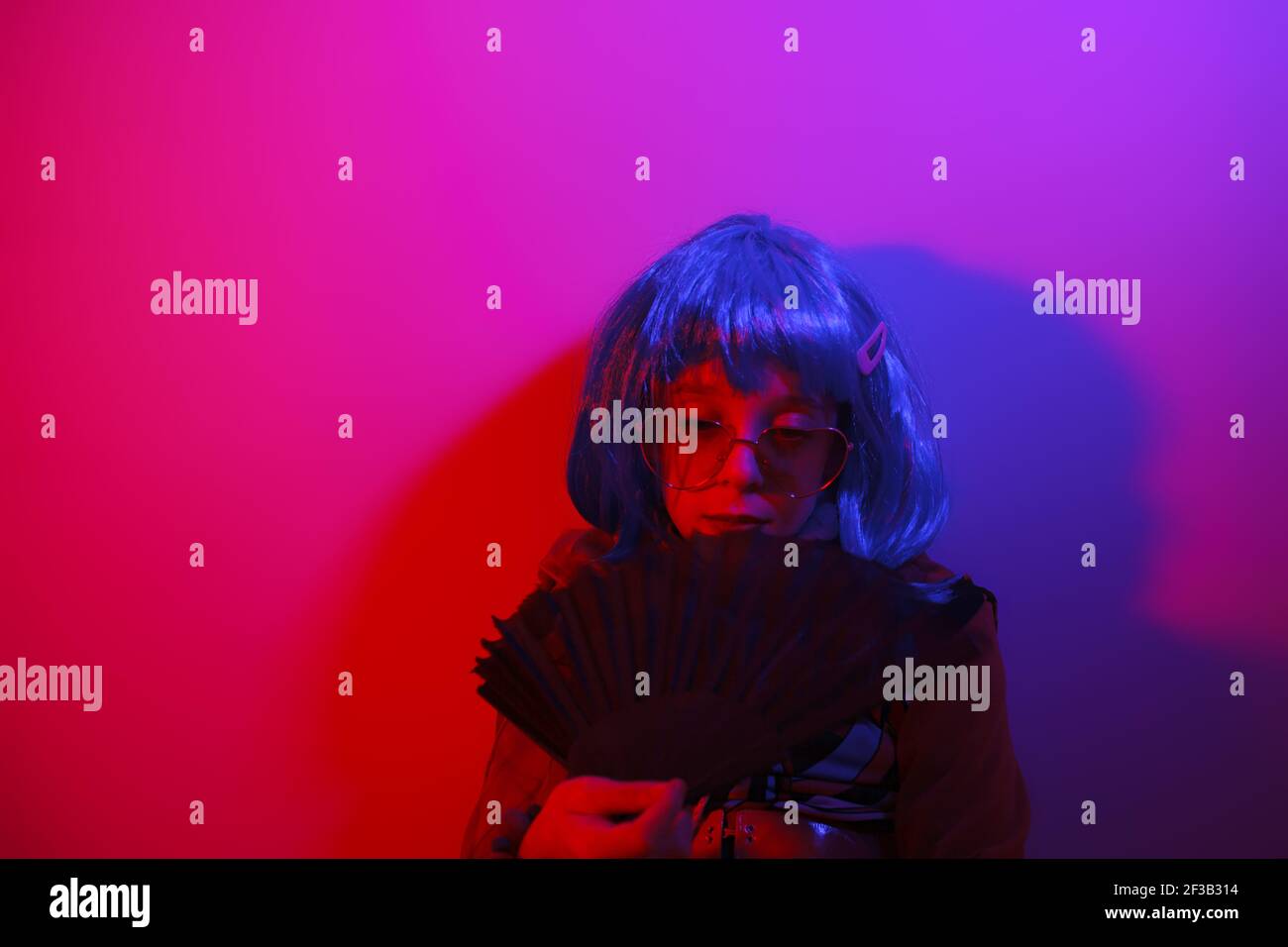 Little girl posing with a fan for a photo shoot on a fuchsia and purple ...