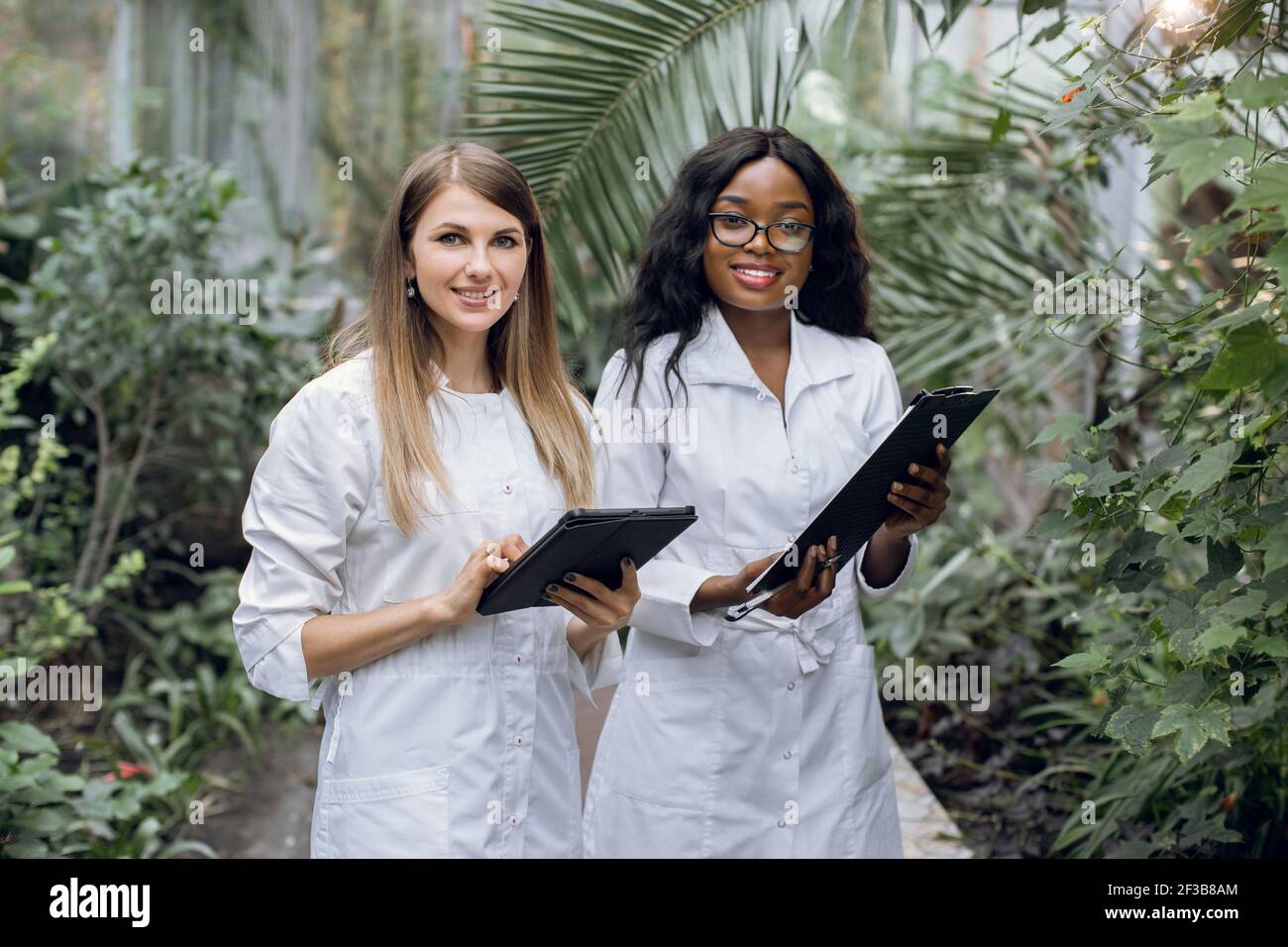 Team of two young pretty multiracial women botanists scientists ...