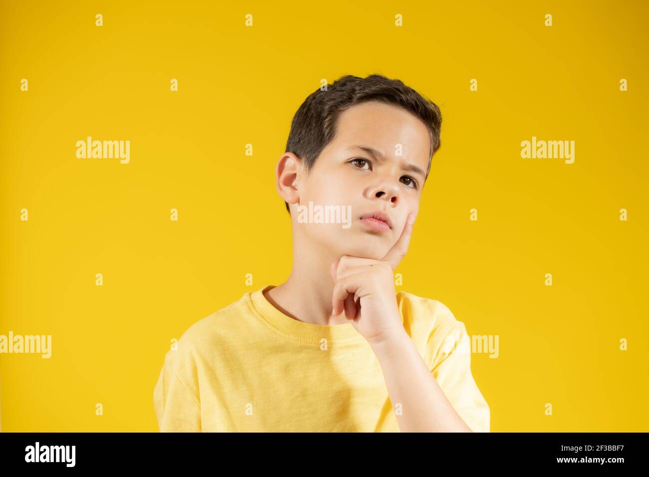 Beautiful young boy pensive isolated over yellow background Stock Photo ...