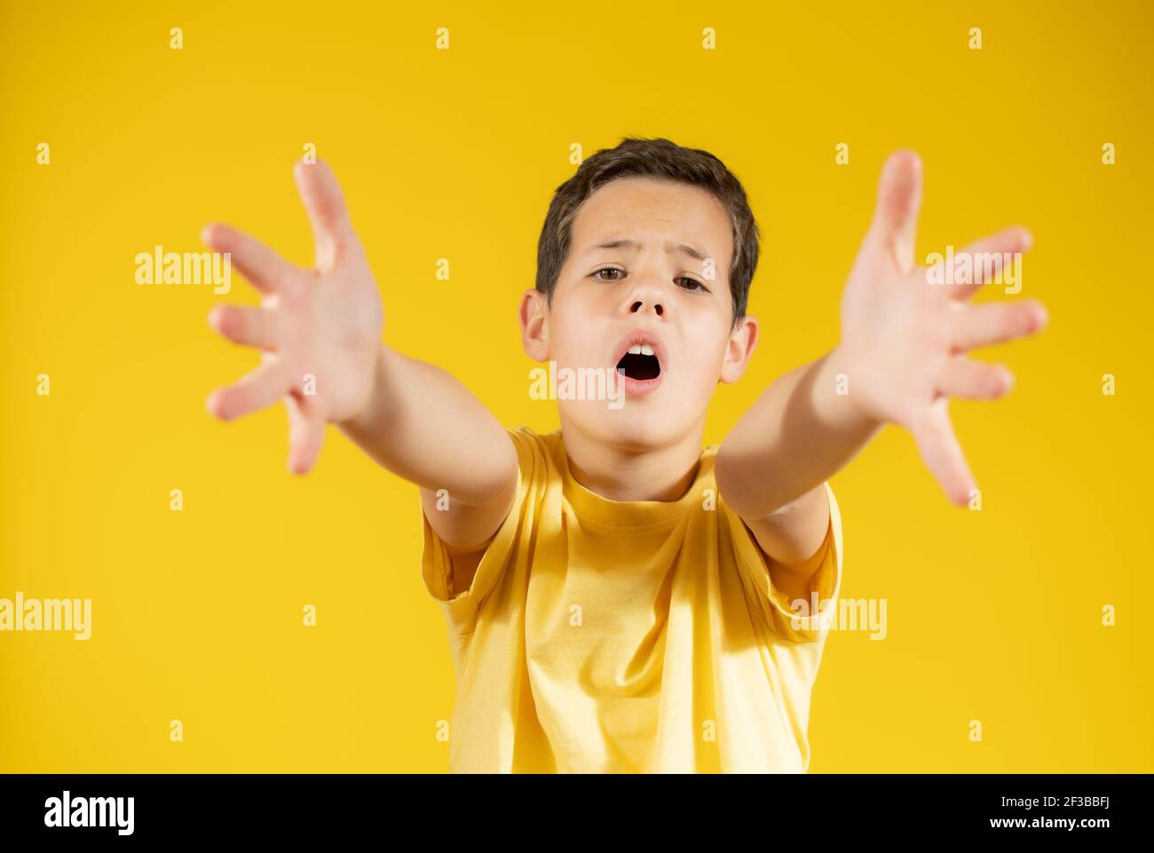 Portrait of young boy making a gesture of despair over yellow ...