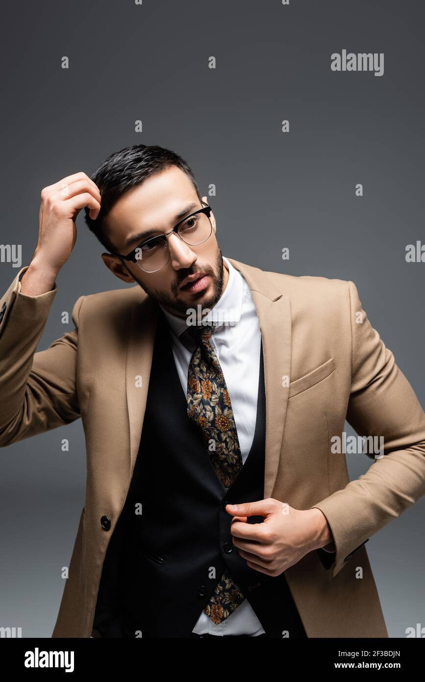 stylish muslim man touching head while looking away on grey Stock Photo ...
