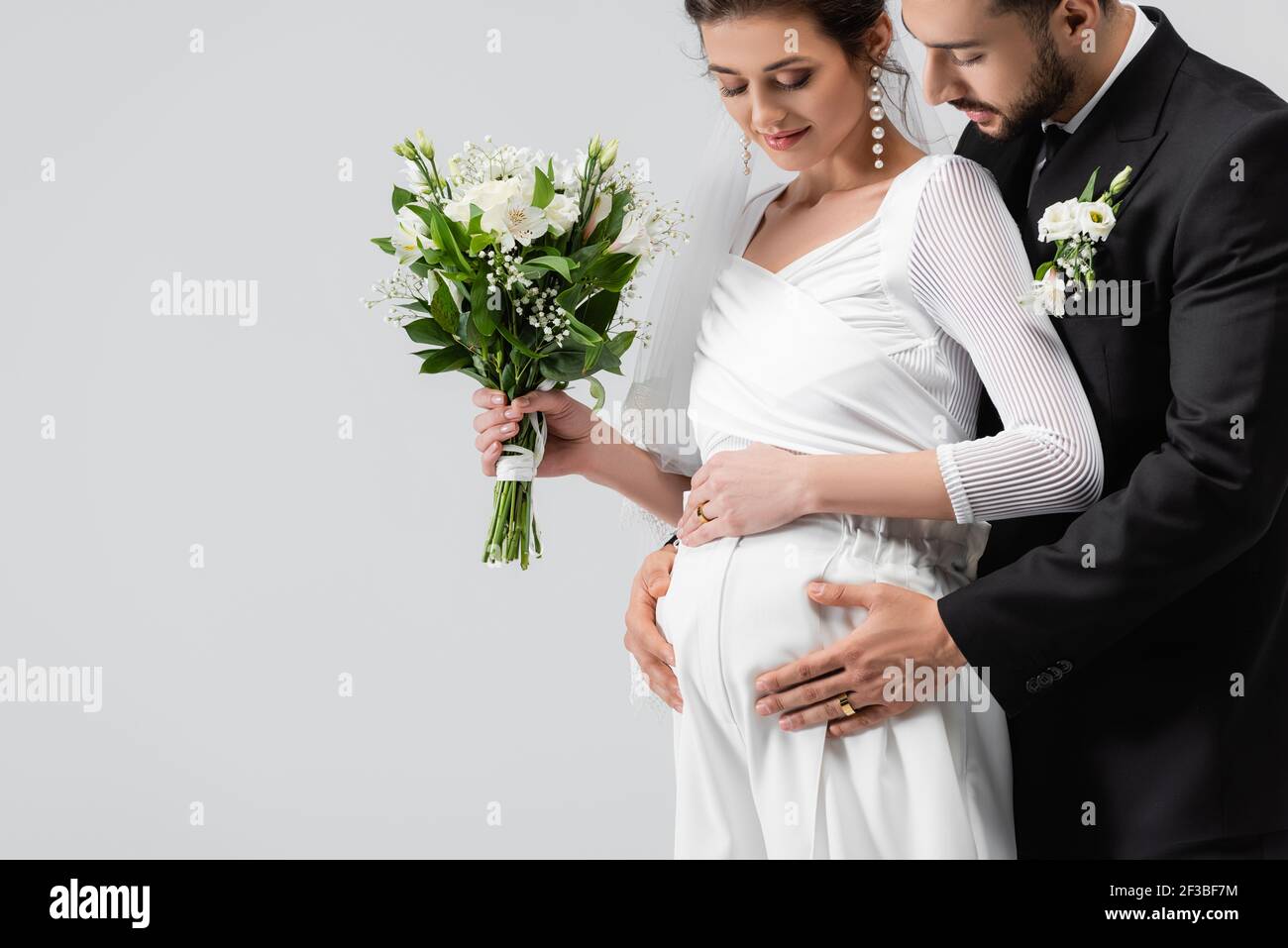Muslim groom looking at belly of pregnant bride with wedding bouquet ...