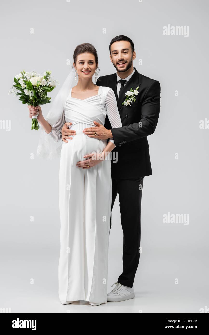 Happy arabian groom hugging pregnant bride and looking at camera on ...