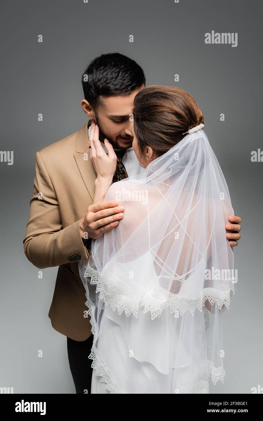 back view of woman in wedding dress touching face of muslim groom ...