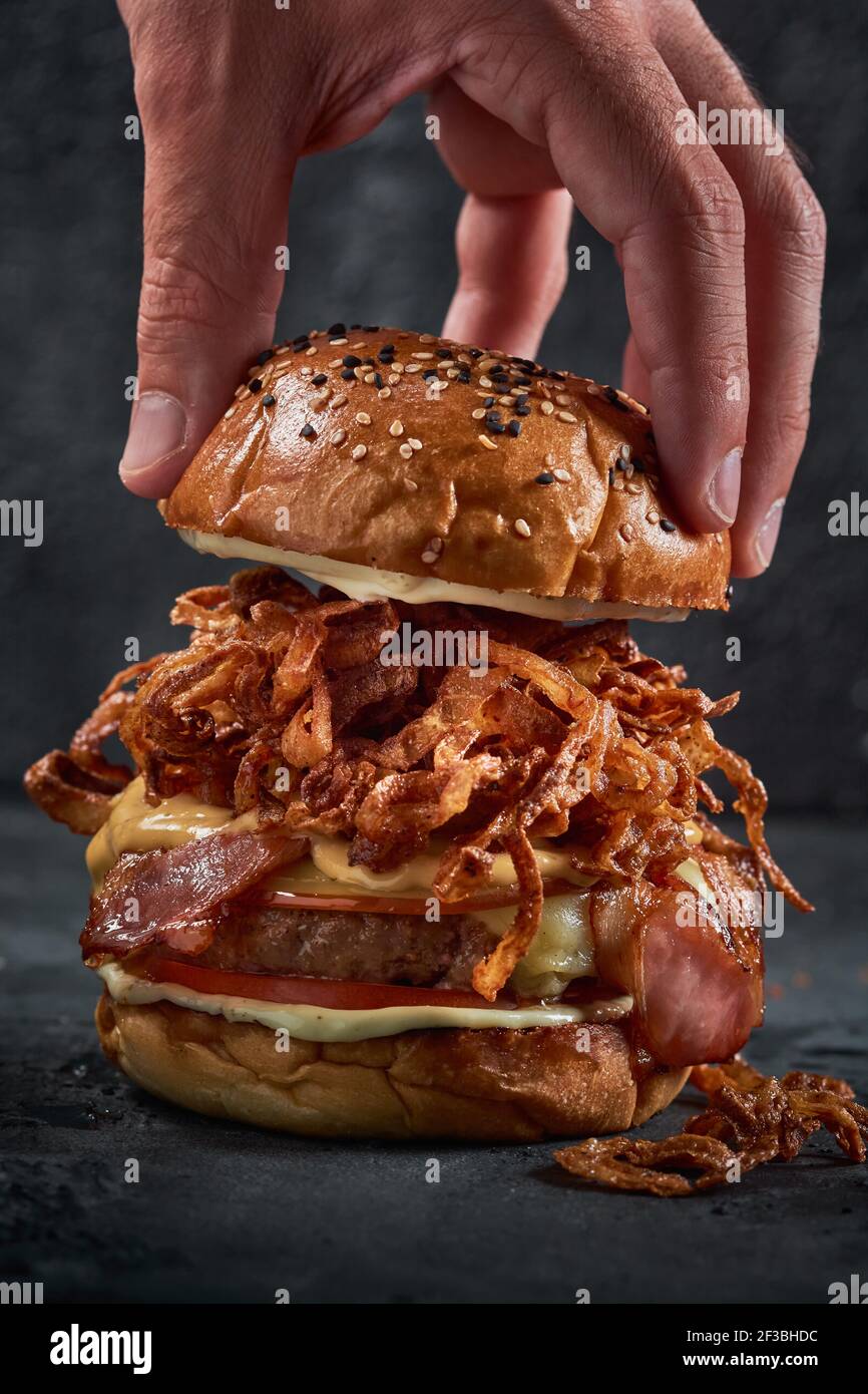 A vertical shot of a male's hand grabbing burger's upper bun Stock ...