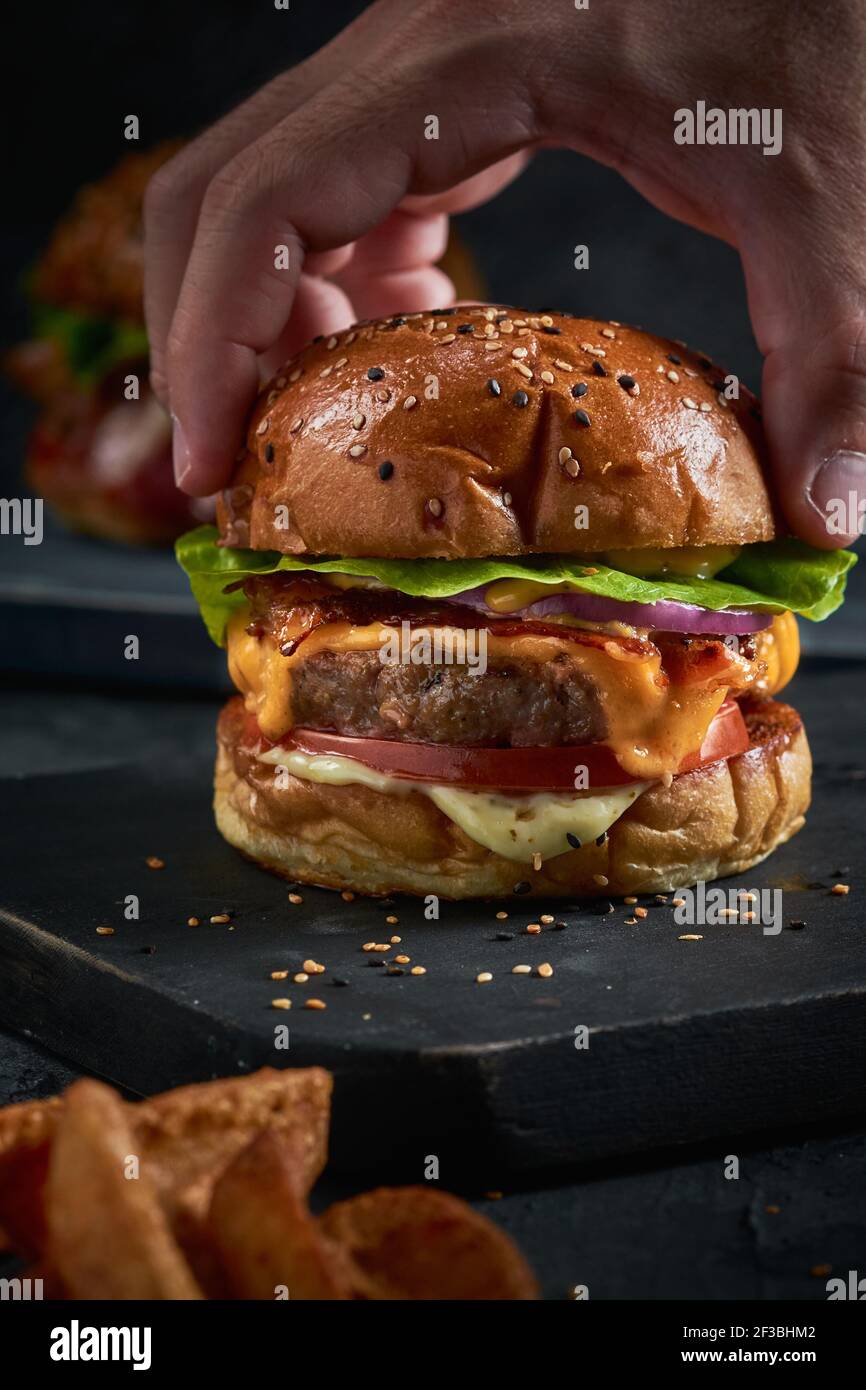 A vertical shot of a male's hand grabbing burger's upper bun Stock ...