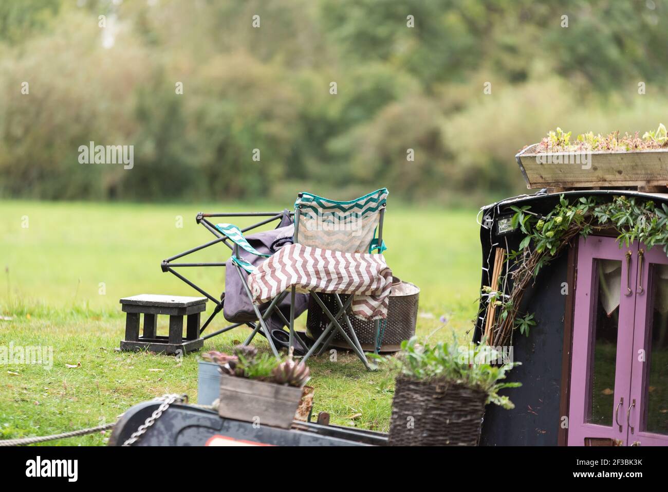 camping chairs on river bank uk next to barge Stock Photo - Alamy