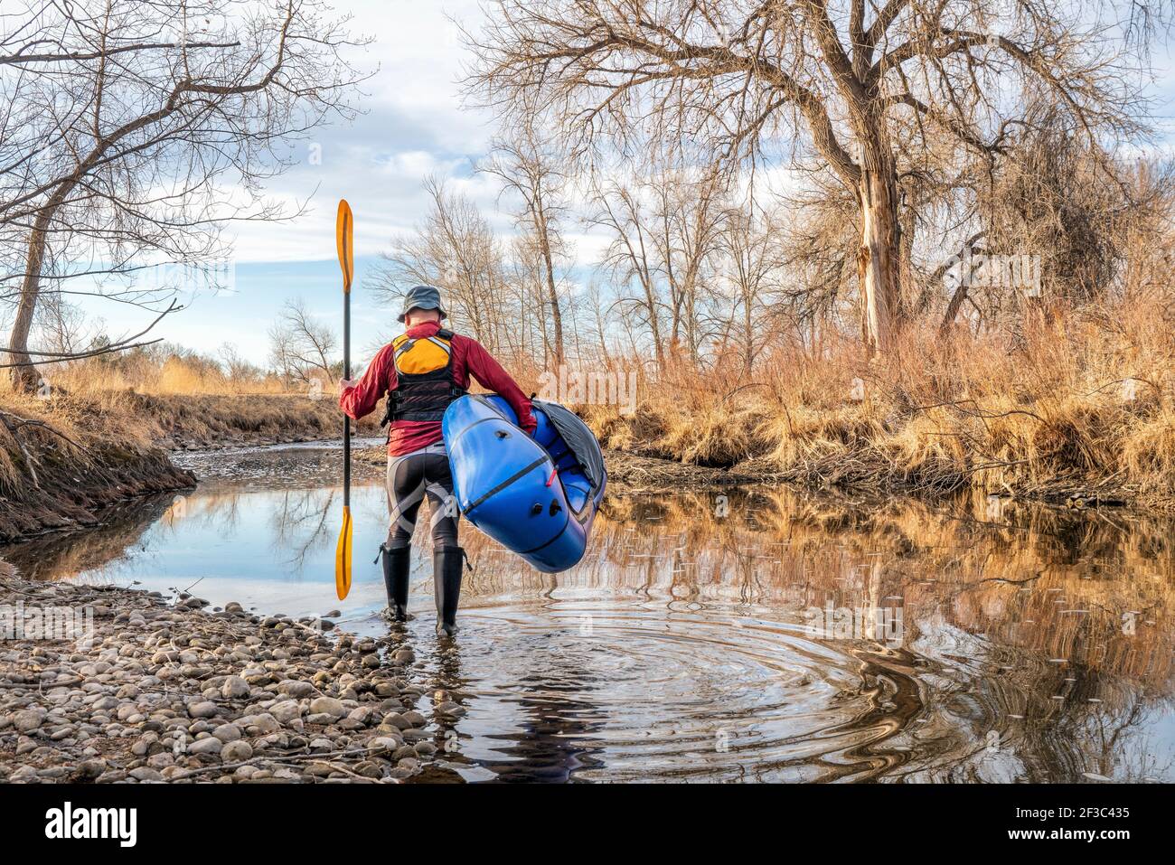 senior male paddler is launching his inflatable packraft on a river in ...