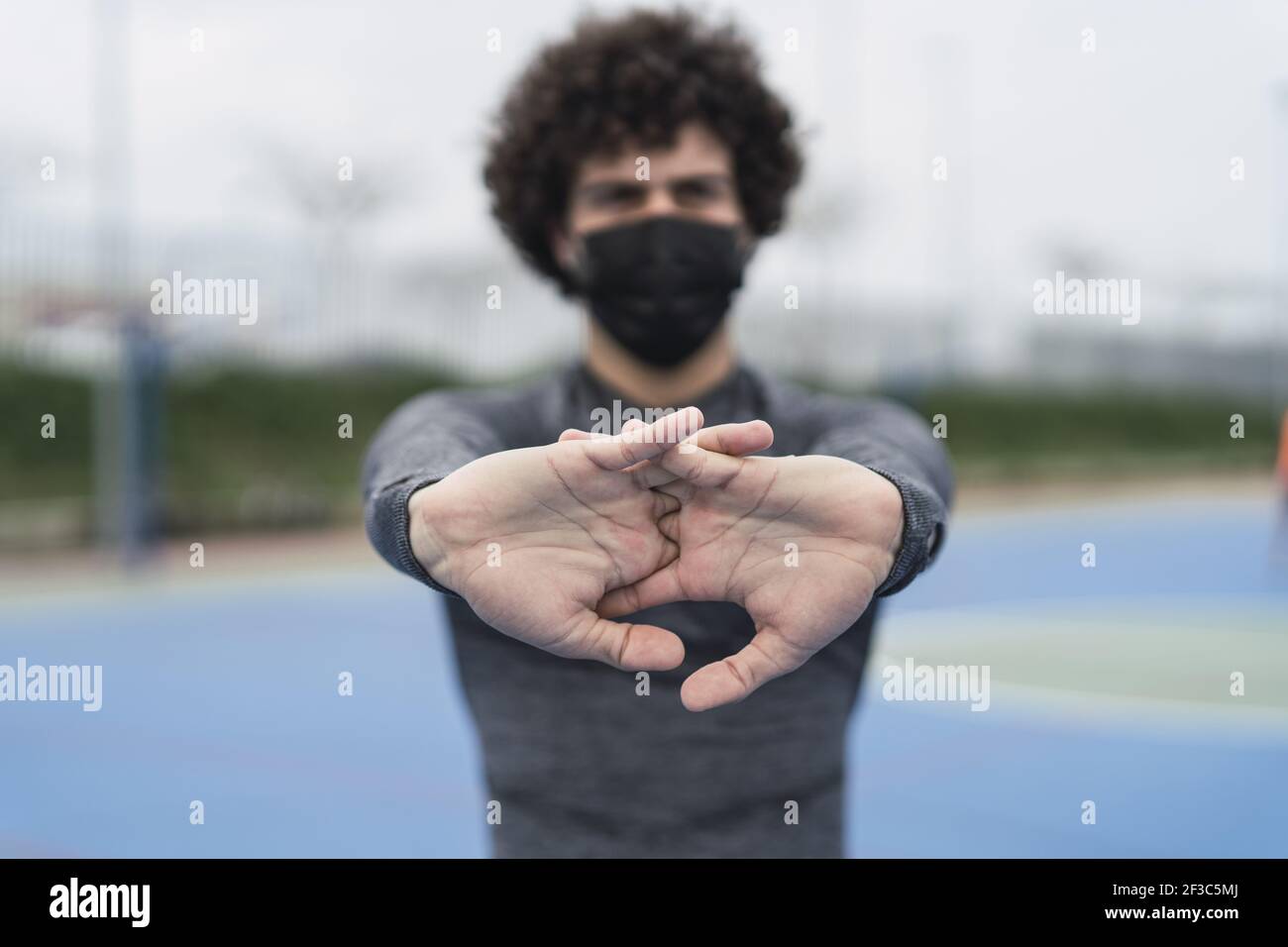 A young athletic male in a black mask has interlaced the fingers and ...
