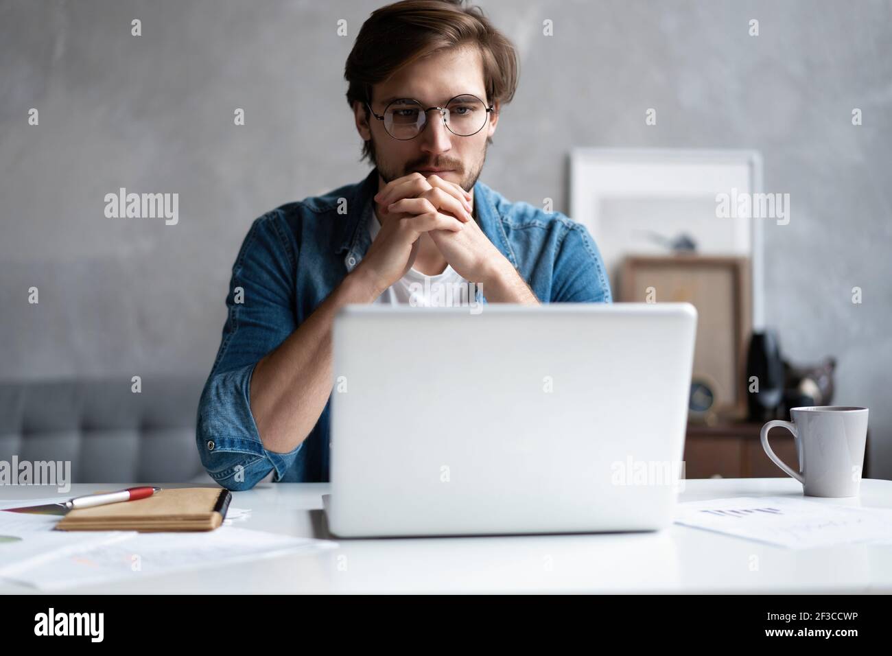 Thoughtful man looking away while sitting at his working place in ...