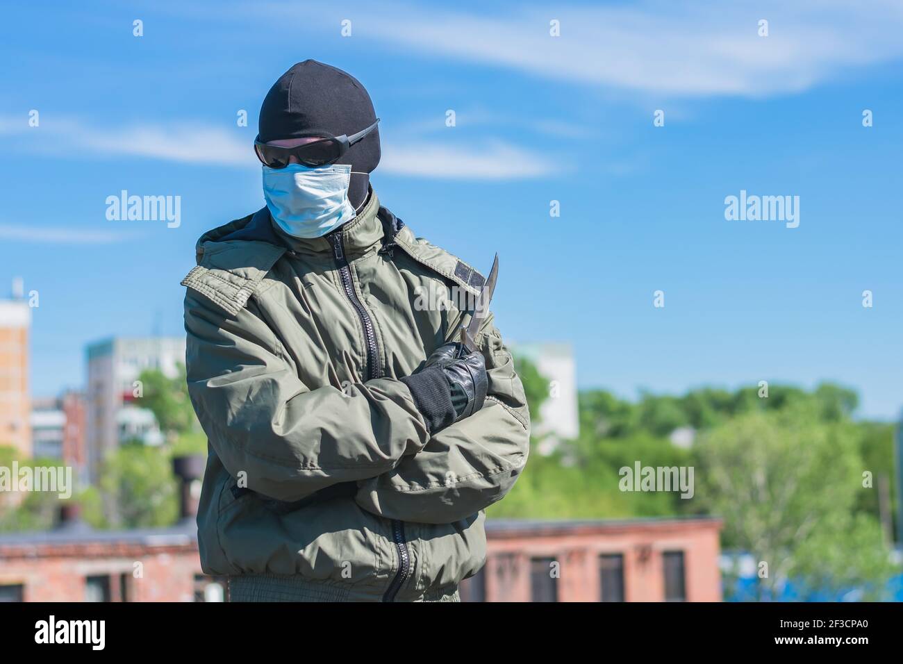 An intruder in a mask and with a weapon stands against the background ...