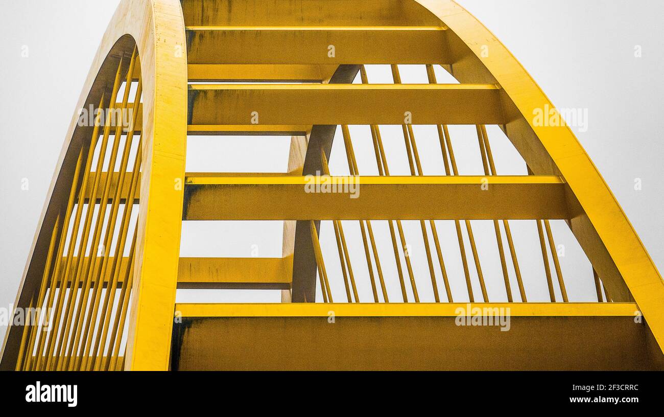 Cable stayed yellow steel bridge under a cloudy sky during day time ...