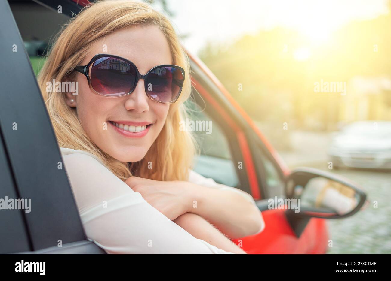 Happy beautiful woman is driving a red car Stock Photo - Alamy