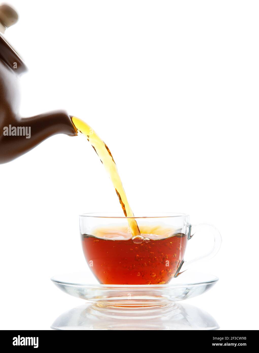Pouring black tea into transparent cup from teapot Stock Photo - Alamy