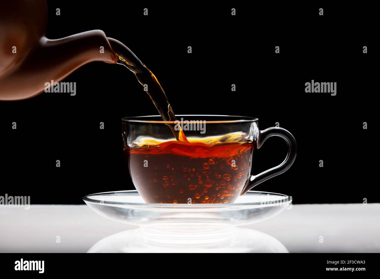 Pouring black tea into transparent cup isolated Stock Photo - Alamy