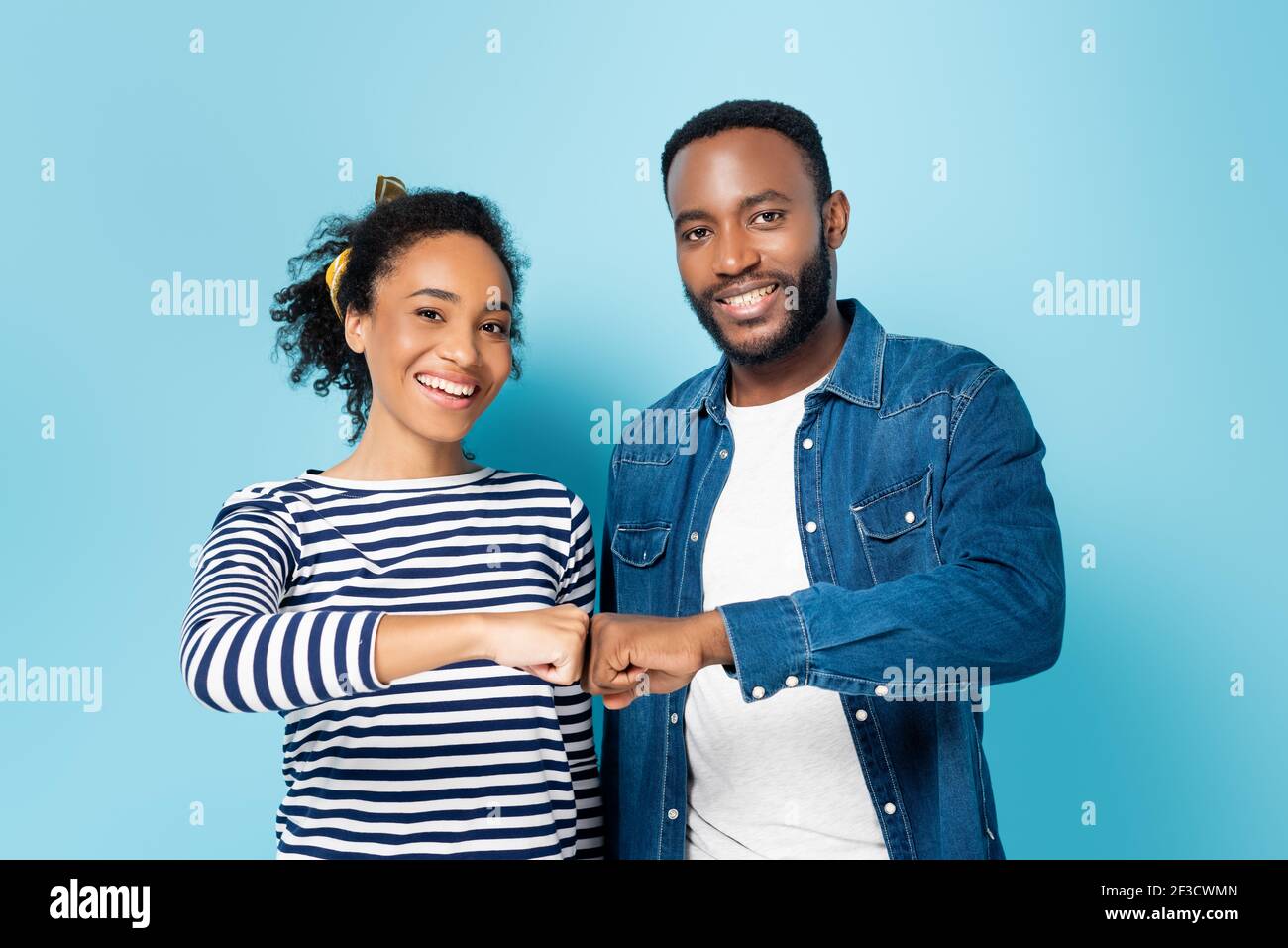 joyful african american couple doing fist bump while looking at camera ...
