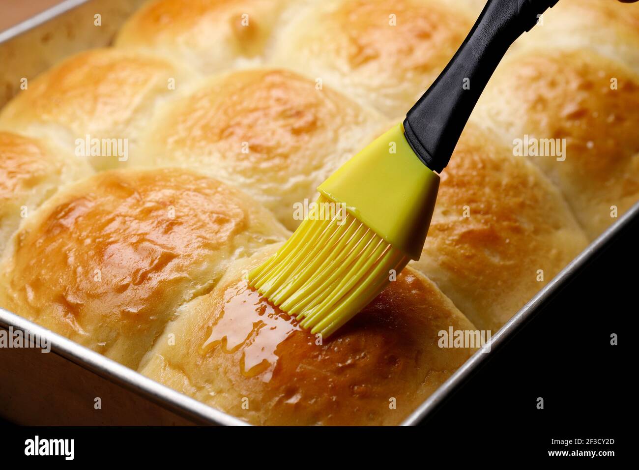 Applying butter on top of freshly baked home made dinner rolls Stock ...