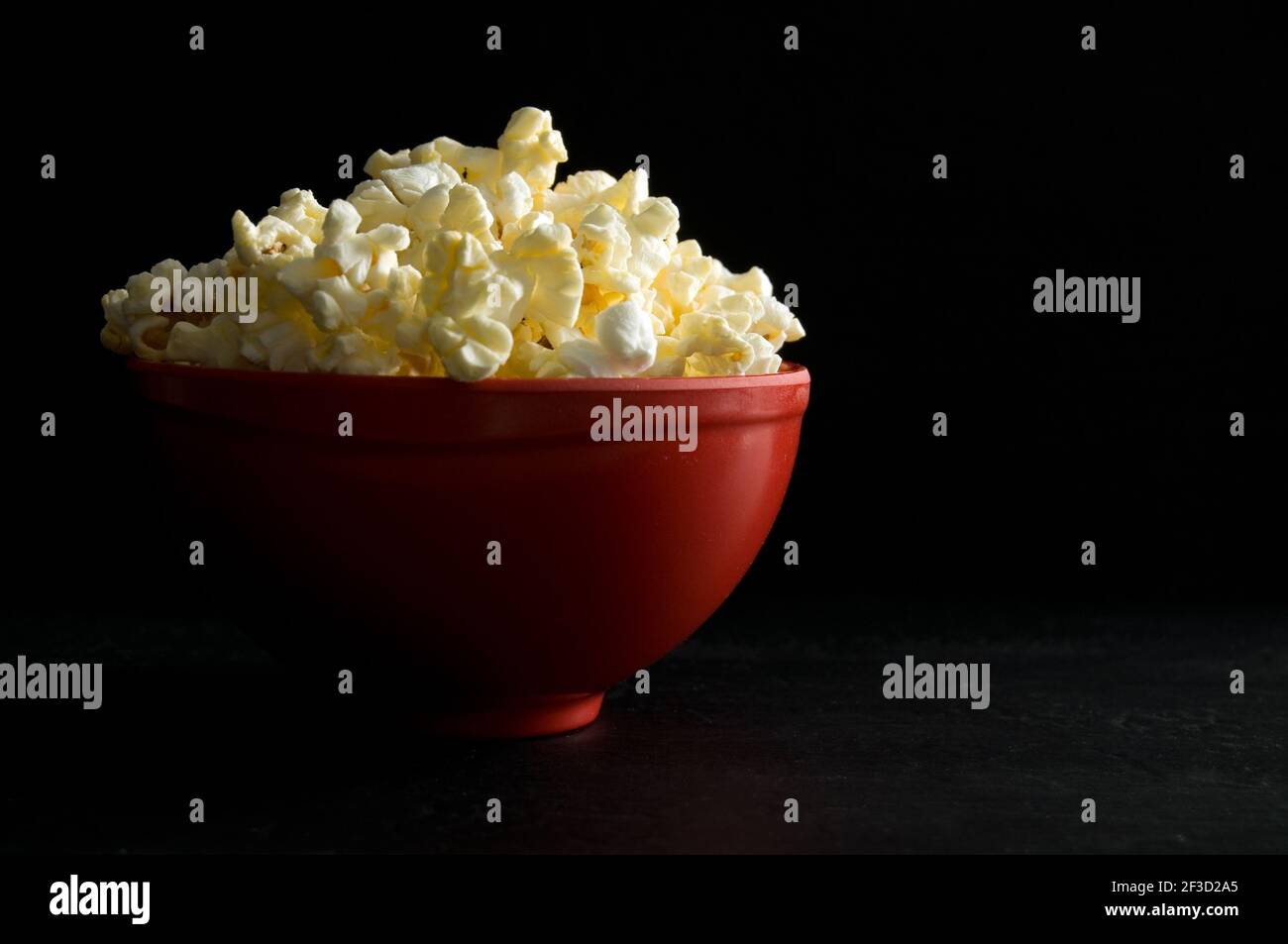 Close Side View of Buttered Popcorn in a Red Bowl Isolated on Black ...