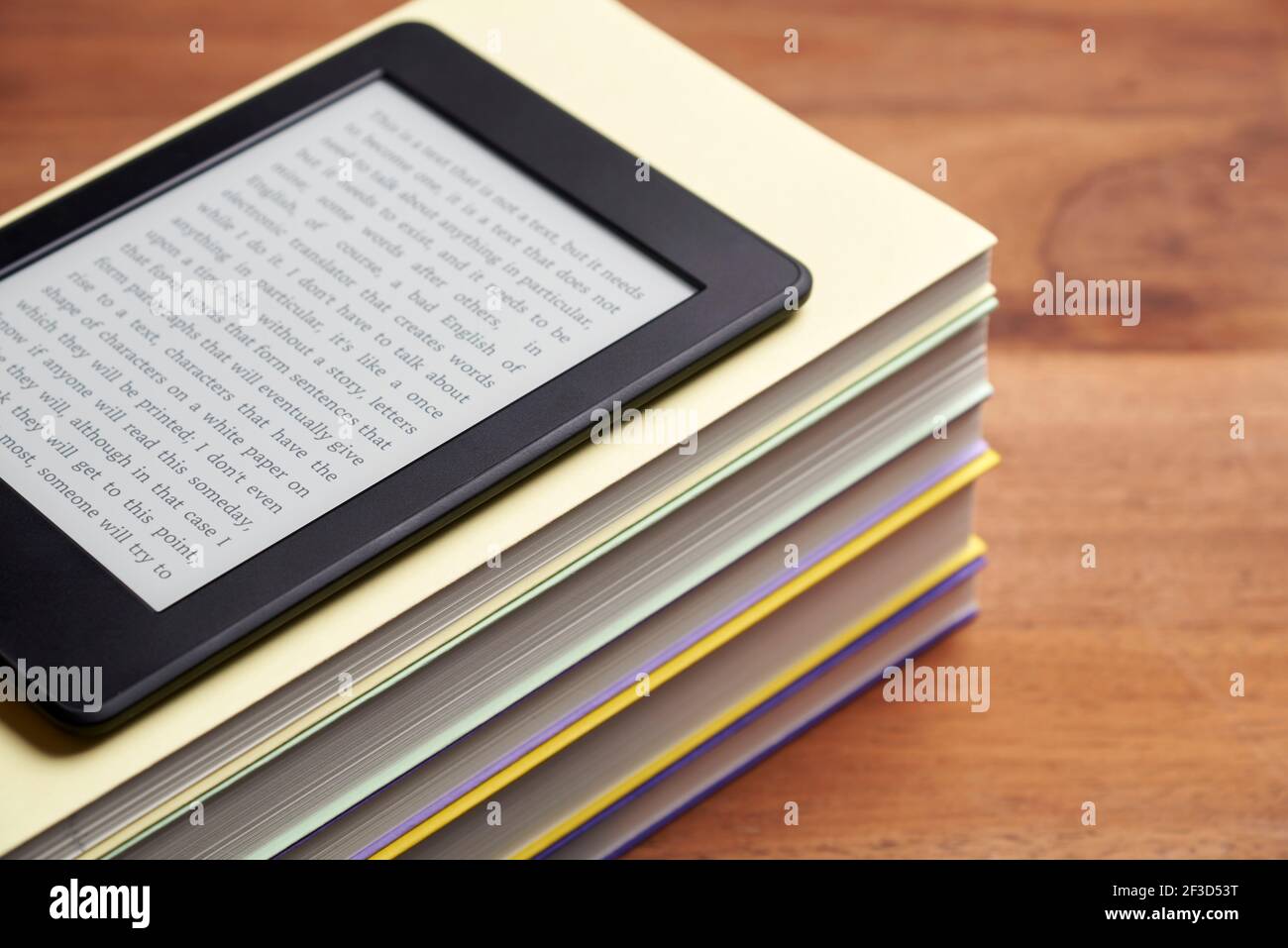 Electronic reader with a text on the screen on a stack of books on a ...
